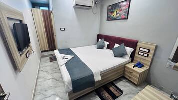 Quarto de hotel com cama, mesa de cabeceira, ar condicionado e um quadro na parede.
