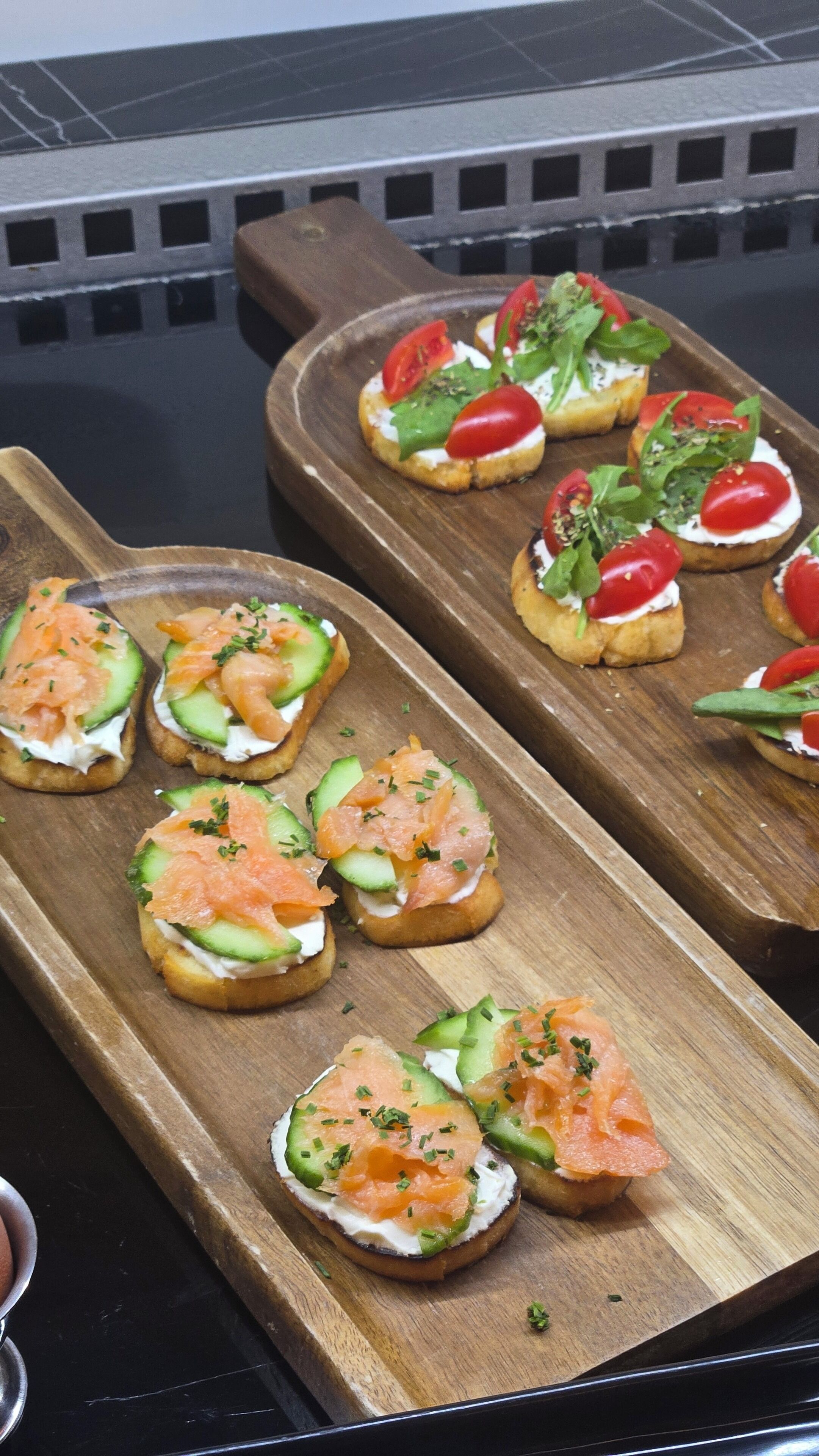 Uma tábua de madeira com diversos aperitivos, incluindo salmão defumado e legumes frescos.