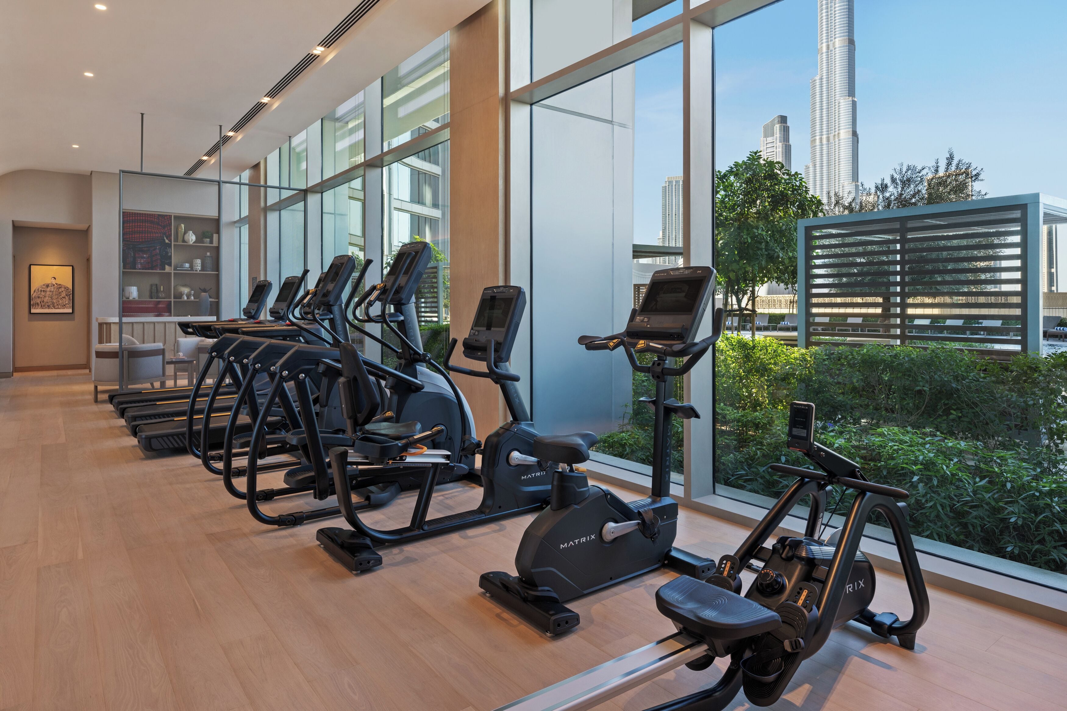 Uma academia moderna com diversos equipamentos de cardio, amplas janelas e vista para o horizonte urbano.