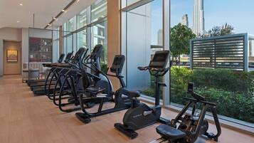 Uma academia moderna com diversos equipamentos de cardio, amplas janelas e vista para o horizonte urbano.