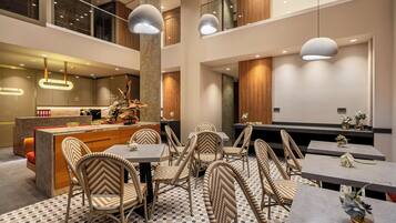 Uma sala de jantar moderna com pé direito alto, iluminação pendente e uma ilha central com assentos.