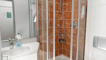 Uma casa de banho moderna com chuveiro de vidro, uma pia com espelho e um dispensador de sabonete líquido.