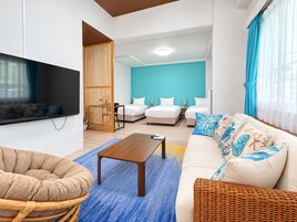 Quarto de hotel moderno com televisão, sofá, mesa de centro e duas camas com cabeceiras combinadas.