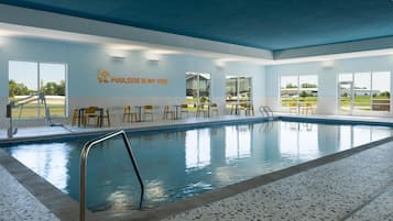Uma piscina interior com vista desobstruída para o exterior, um logotipo na parede, e um conjunto de cadeiras e mesas amarelas.