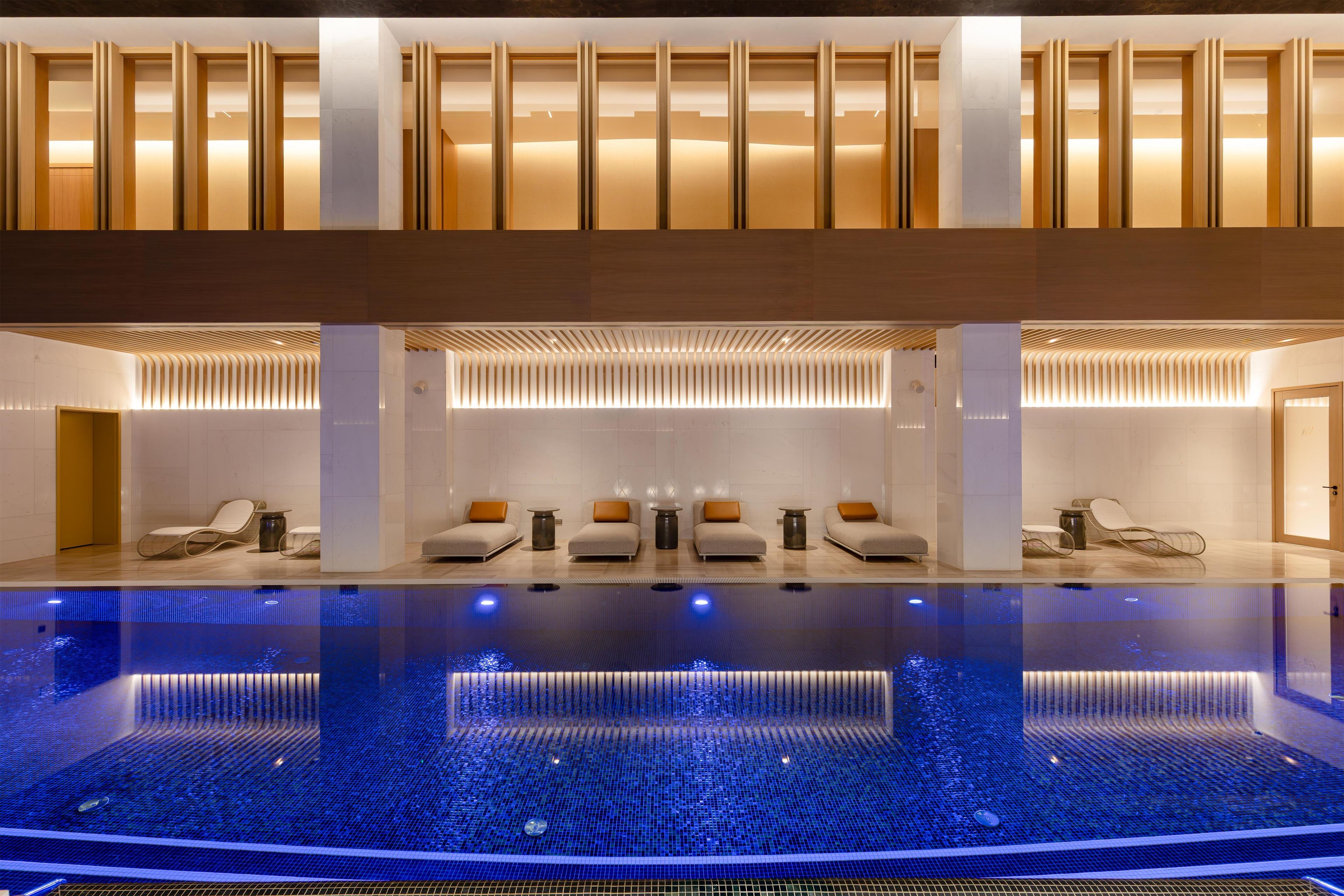 Uma área de piscina interna moderna, com assentos e vista para o andar superior.