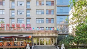 Um hotel com vários andares, entrada imponente, área de jardim e restaurante visível.