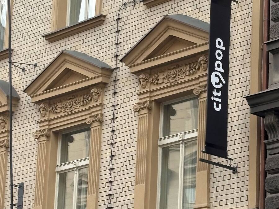 Fachada de edifício com placa preta que diz "cit pop" e elementos arquitetônicos decorativos.