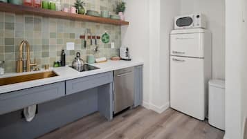 Uma cozinha equipada com pia, chaleira, micro-ondas e geladeira.
