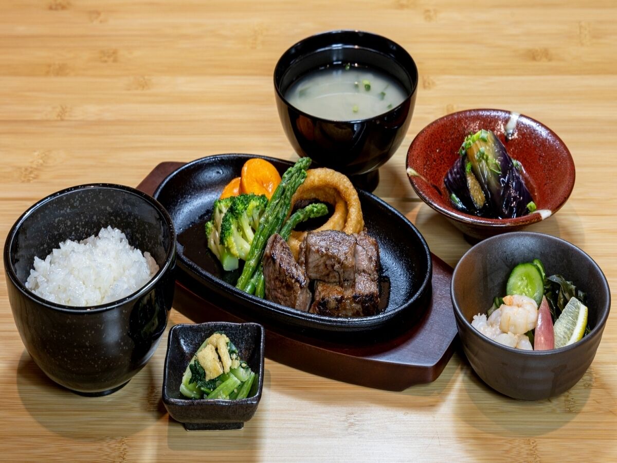 Uma refeição japonesa tradicional com arroz, carne, legumes e sopa.