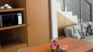 Cozinha moderna com armários de madeira, micro-ondas e área de refeições com mesa e cadeiras de madeira.