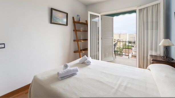 Quarto de hotel com cama, escada de madeira, varanda e uma vista, além de um quadro na parede.