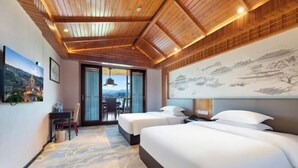 Quarto de hotel com duas camas, um espaço de refeições e uma janela grande com vista.