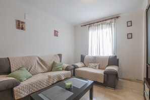 Sala de estar com dois sofás, uma mesa de centro e uma janela com cortinas.