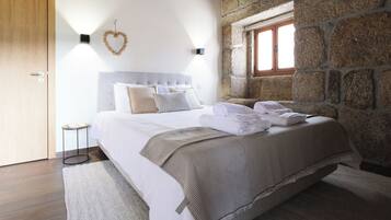 Quarto com cama grande, decoração de parede em formato de coração, parede de pedra e janela.
