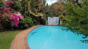 Piscina cercada por vegetação exuberante e plantas floridas.