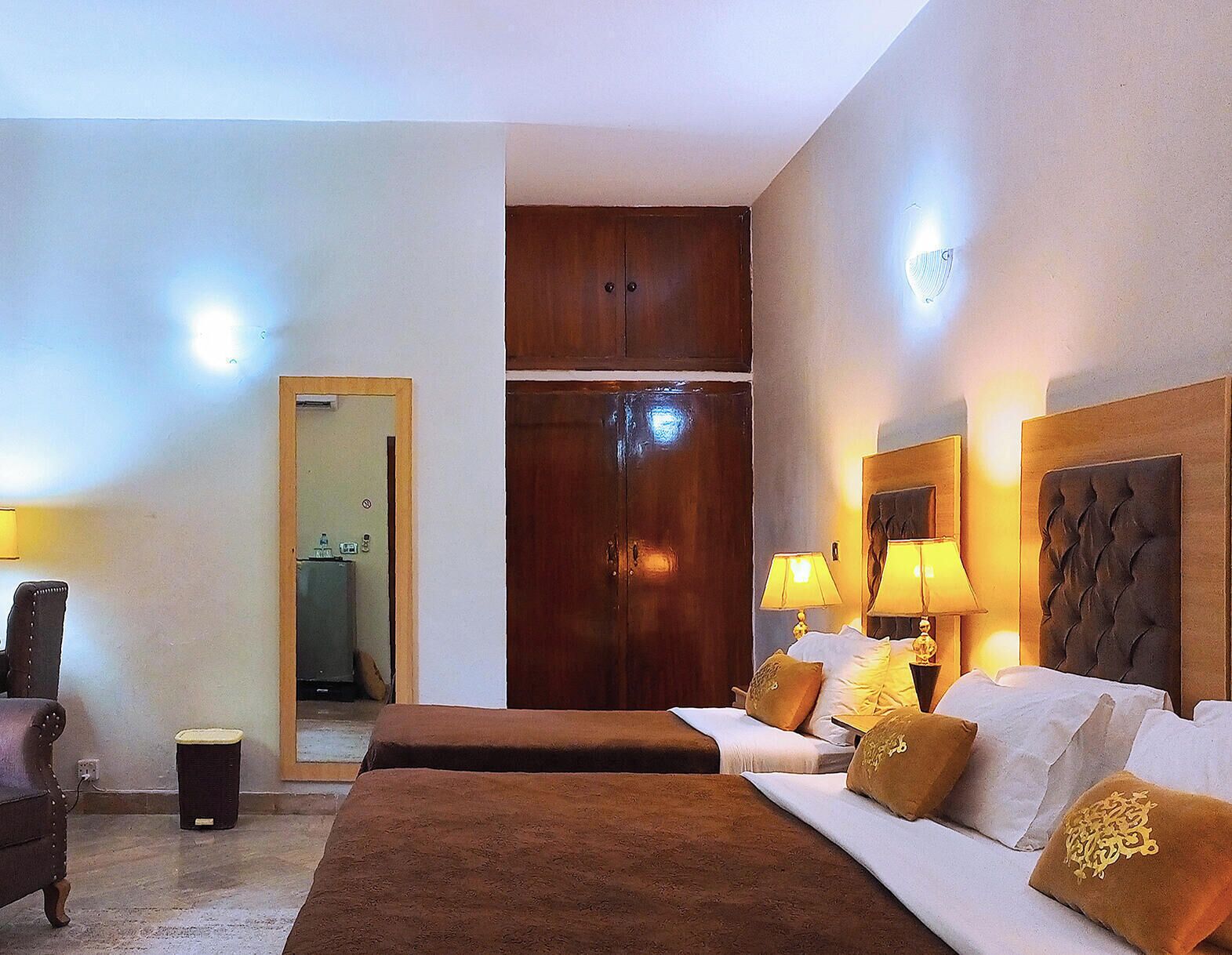 Quarto de hotel com cama, abajures, guarda-roupa e espelho.