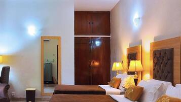 Quarto de hotel com cama, abajures, guarda-roupa e espelho.