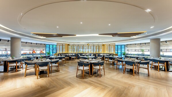 Um restaurante espaçoso com várias áreas de estar, janelas amplas e um design de interiores moderno.