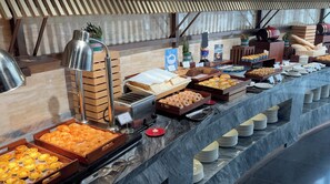Buffet com diversos itens de comida, incluindo pães, bolos e produtos de panificação.