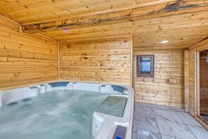 Uma cabana de madeira com hidromassagem, paredes de madeira e piso de azulejo.