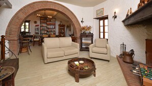 Uma sala de estar acolhedora com um arco de tijolos, lareira e estante cheia de livros.