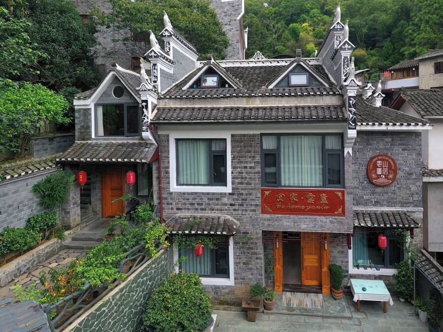 Um edifício tradicional chinês com telhado em telhas, porta de madeira e uma placa com caracteres chineses.