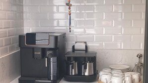 Uma cozinha compacta com cafeteira, chaleira e bule sobre o balcão.