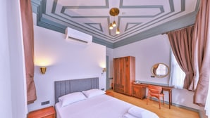 Quarto de hotel com uma cama grande, uma escrivaninha, um guarda-roupa e um espelho.