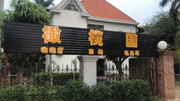 Placa com caracteres chineses, portão e edifício com telhado vermelho.