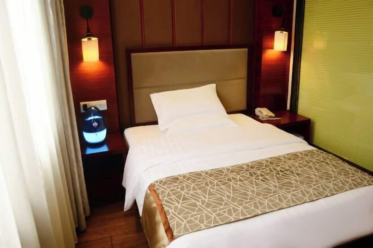 Quarto de hotel com cama, abajures, telefone e luminária na parede.