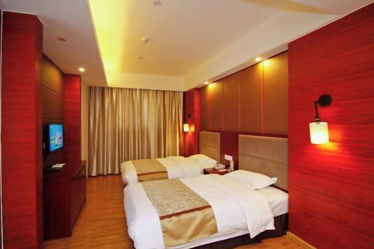 Quarto de hotel com duas camas, uma televisão e uma escrivaninha.
