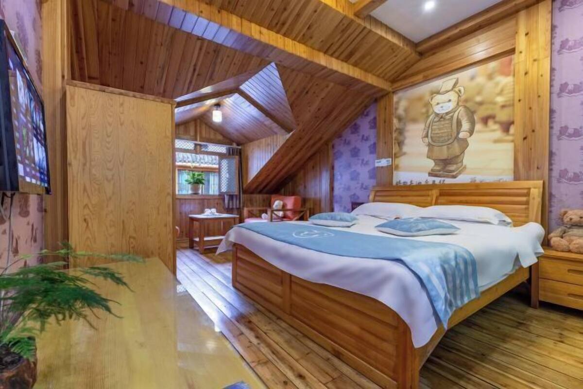 Quarto de madeira com uma cama, uma mesinha e um urso ilustrado na parede.