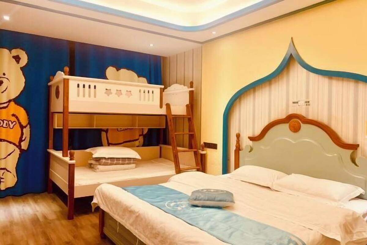 Quarto com beliches, um mural e uma cama com cabeceira.