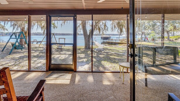 Quarto moderno com grandes portas de vidro que dão para a praia, ventilador de teto e teto de madeira.