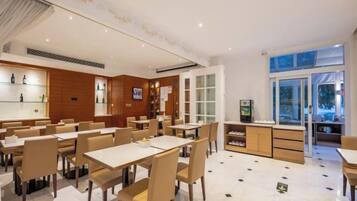 Restaurante moderno com várias mesas e cadeiras, área de bar e vista para o exterior por grandes janelas.