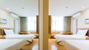 Quarto de hotel com duas camas, piso de madeira e uma janela grande com cortinas.