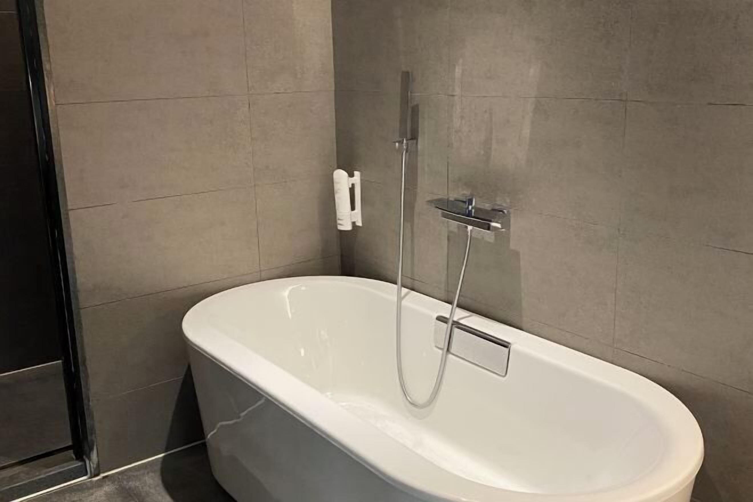 Uma casa de banho moderna com uma banheira independente, um chuveiro manual e um porta-toalhas.