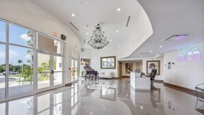 Um hall espaçoso com um lustre imponente, um piano e uma mesa de recepção.