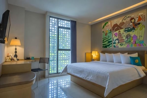 Quarto de hotel com cama, escrivaninha, cadeira e uma janela grande com vista.
