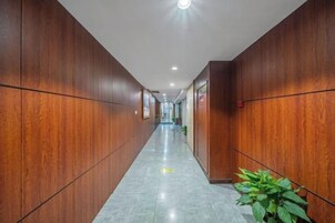 Um corredor comprido e estreito, com painéis de madeira nas paredes e chão de azulejos.