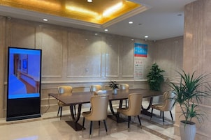 Sala de conferências com tela digital, uma mesa grande e várias cadeiras.
