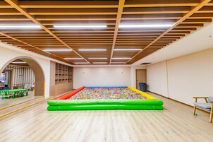 Quarto com uma piscina inflável grande, piso de madeira e teto com vigas de madeira.