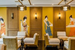 Quarto com pinturas tradicionais em estilo japonês nas paredes, painéis de madeira e disposição moderna dos assentos.