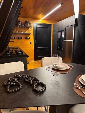 Uma cozinha moderna com uma mesa de jantar posta para dois, uma geladeira e um fogão.