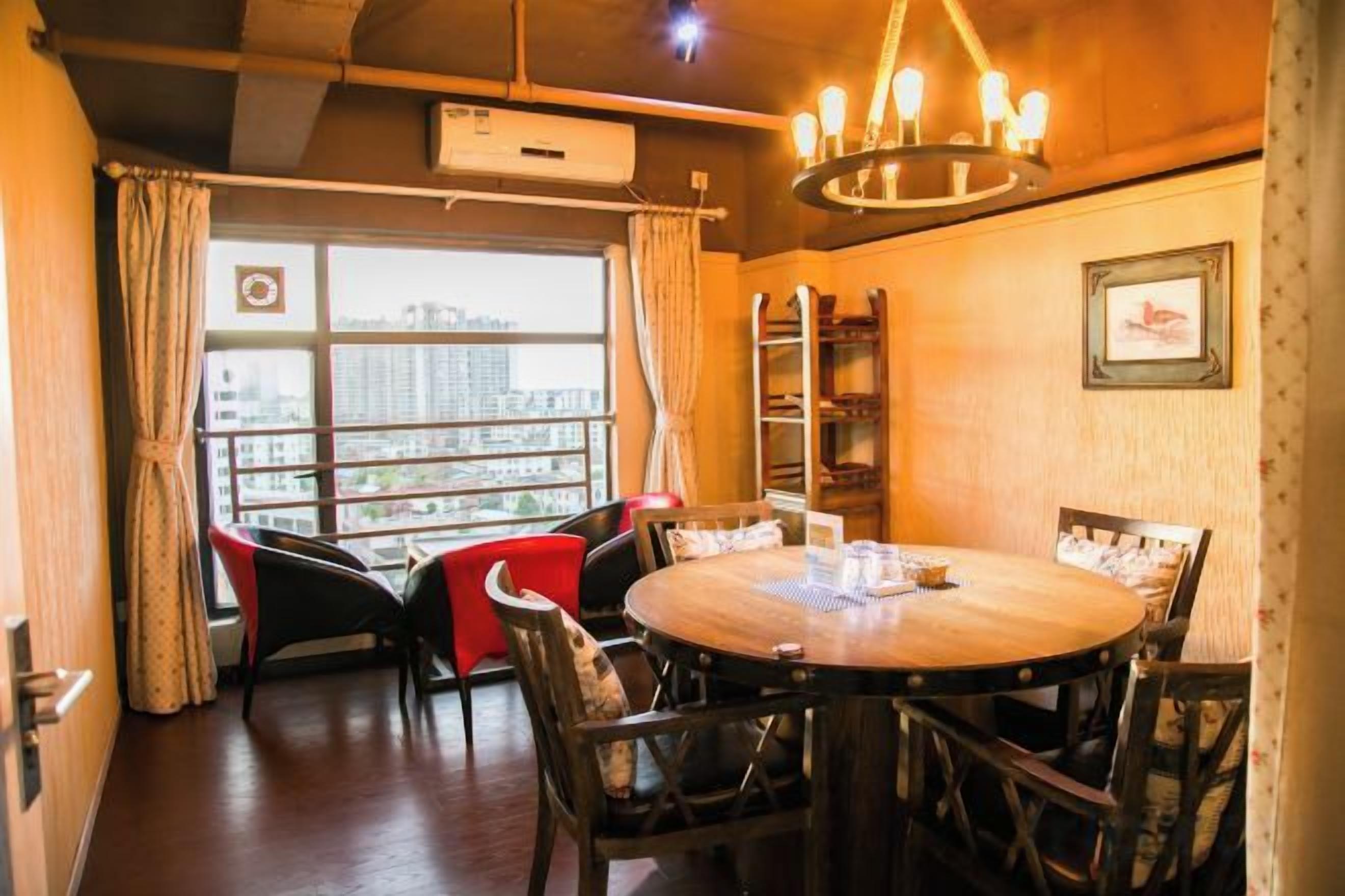 Uma sala de jantar com uma mesa redonda, cadeiras e um lustre.