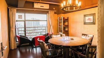 Uma sala de jantar com uma mesa redonda, cadeiras e um lustre.