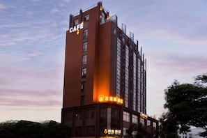 Um hotel alto com um letreiro chamativo 'CAFE' na lateral, vários andares e design arquitetônico moderno.