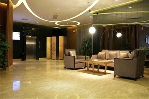 Um hall de entrada com balcão de recepção, área de estar e uma grande planta.