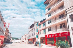 Rua com edifícios altos, fachada vermelha e céu limpo.