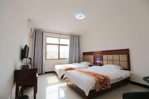 Quarto de hotel com duas camas, uma escrivaninha, uma cadeira, uma televisão e uma janela com cortinas.